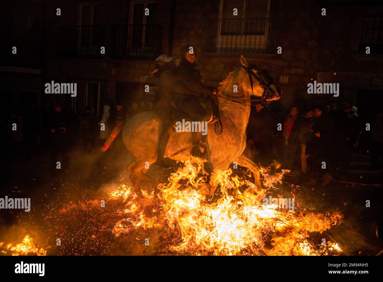 A rider and a companion mounted on a horse cross a bonfire during the ...