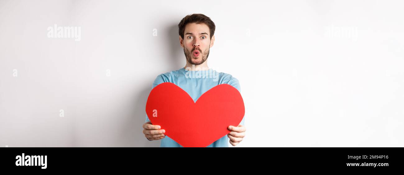 Young handsome man showing big red valentines day heart, being in love ...