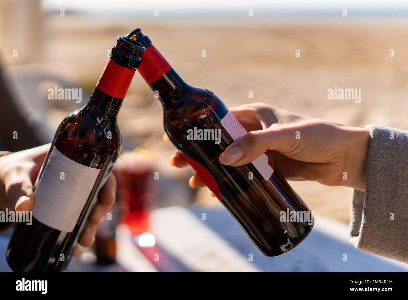 Crop anonymous male and female clinking bottles of beer while ...