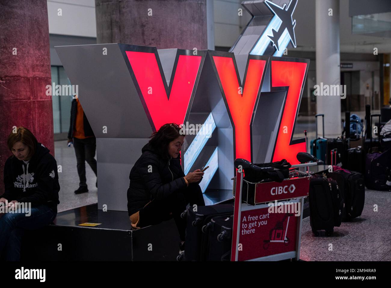 Toronto, Canada. 16th Jan, 2023. A woman with luggage sits under a ...