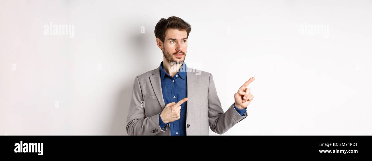 Handsome businessman in suit pointing, looking left at logo with ...