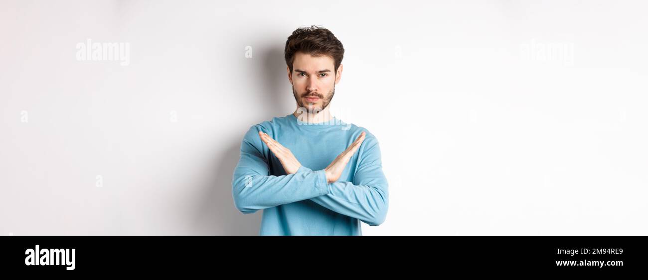 Young man with beard looking serious, making cross gesture to stop ...