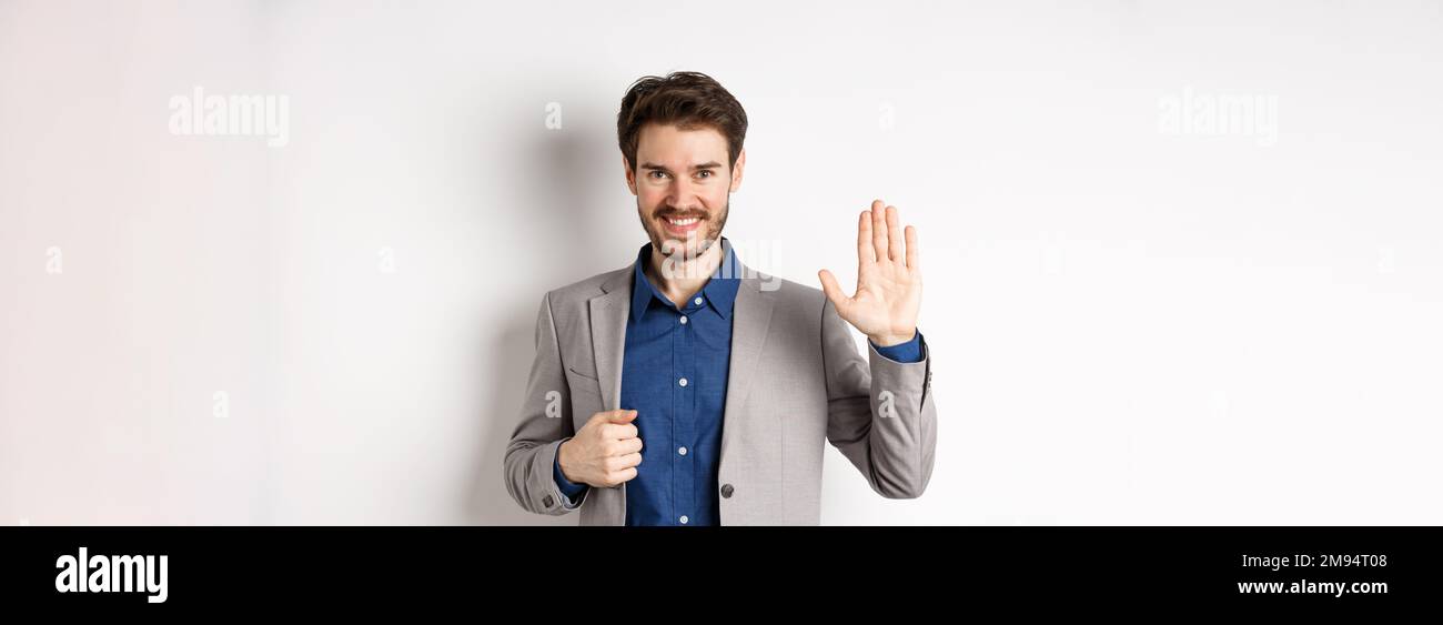 Smiling handsome businessman in suit waving hand, greeting friend with ...