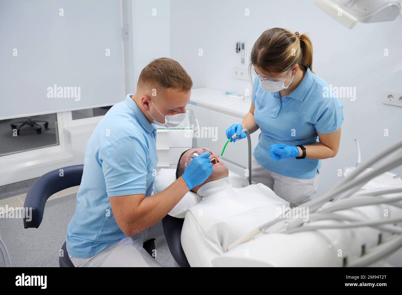 dentist patient assistant during her dental treatment at dentist. Dental doctors treating a male ...