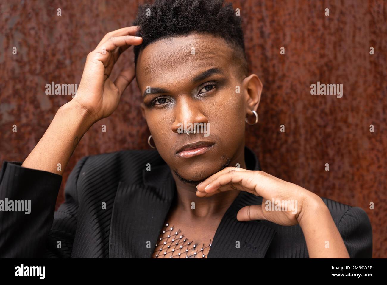 Portrait of a model man of black ethnicity in a fashion pose on a brown ...