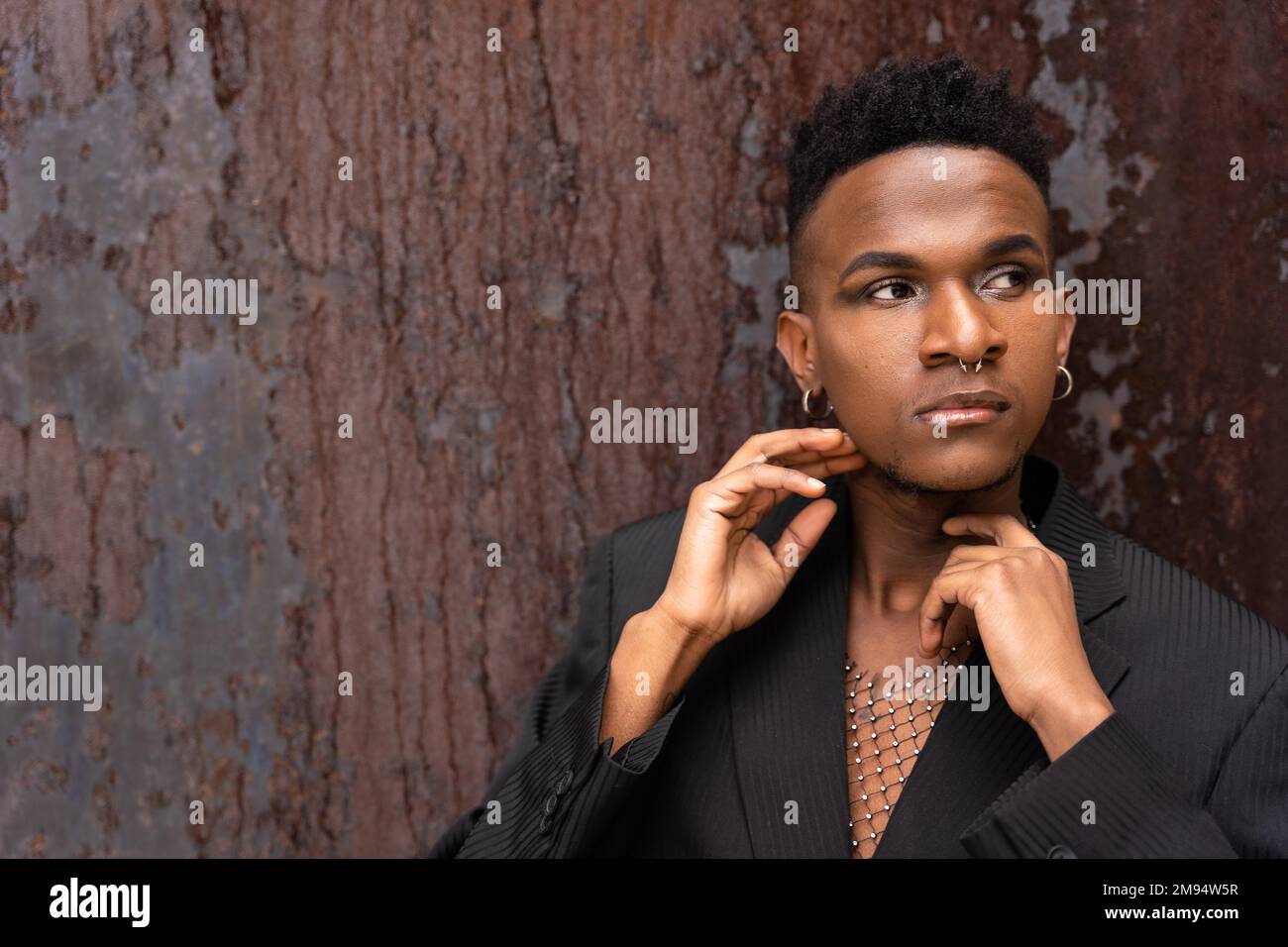 A black ethnic man in a fashion pose on a brown metallic background ...