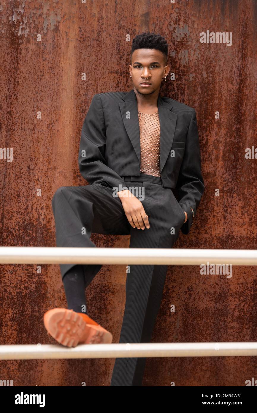 A male model of black ethnicity in a fashion pose on a brown metallic ...