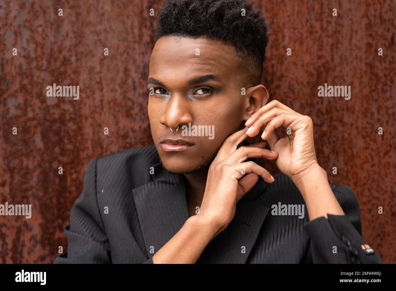 Portrait of a model man of black ethnicity in a fashion pose on a brown ...