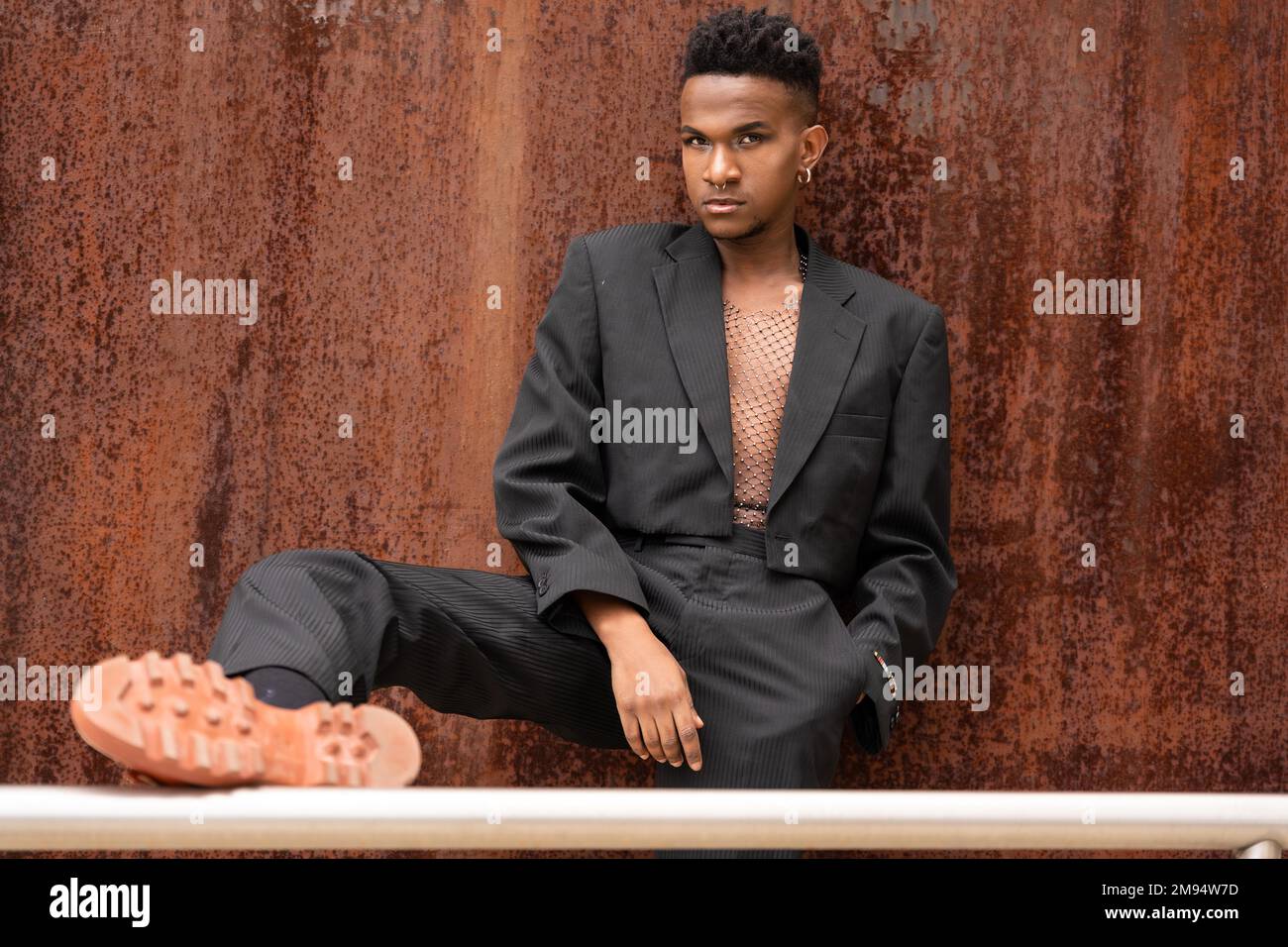 A male model of black ethnicity in a fashion pose on a brown metallic ...