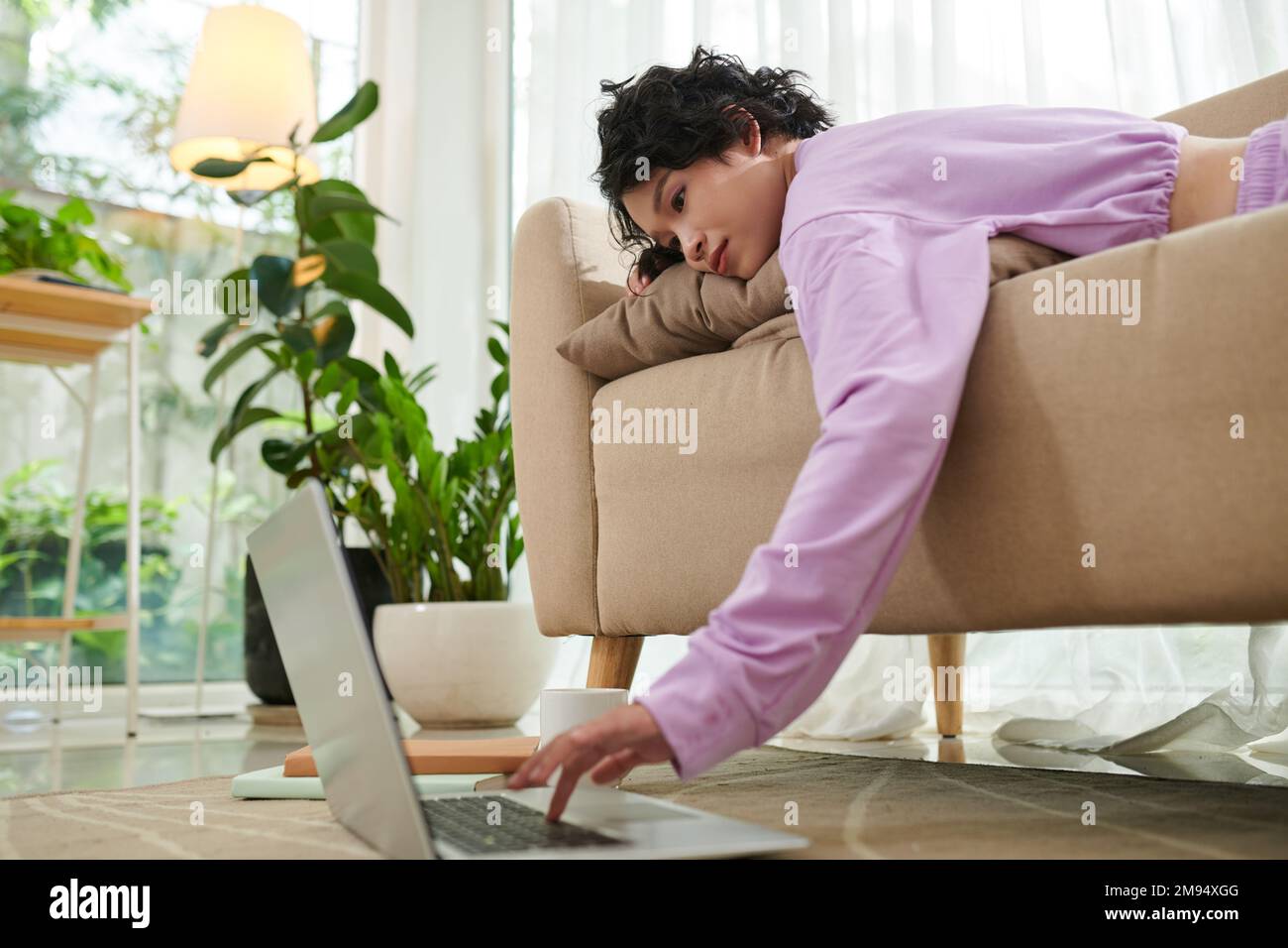 Lazy teenage girl relaxing on sofa and watching new video of favorite ...