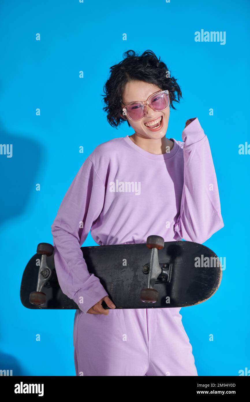 Joyful excited teenage girl with skateboard making fist pump gesture ...