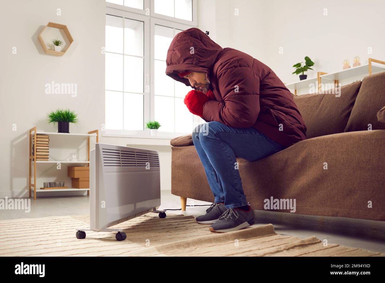 Warmly Dressed Man Warming Hands At Electric Heater Feeling Cold At
