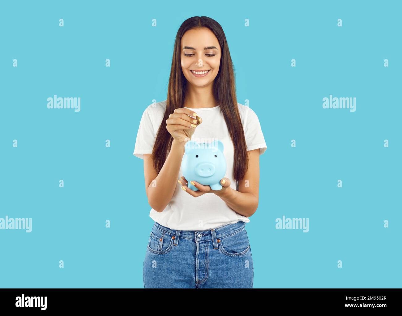 Portrait of happy woman who puts coin in piggy bank, saving money for ...