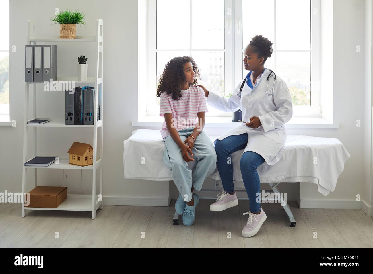 Caring Doctor Touches Shoulder Of Excited Teenage Girl Who Is Worried