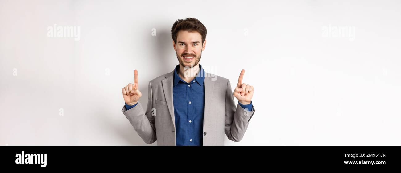Confident successful businessman pointing fingers up, smiling and ...