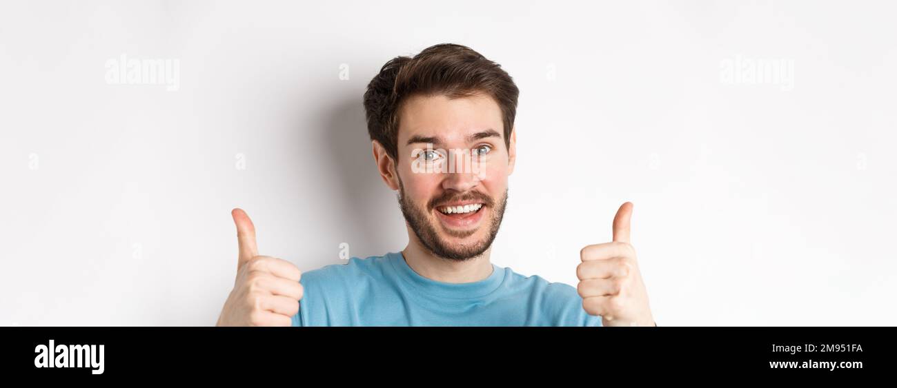 Close-up of cheerful man say yes, showing thumbs up in approval, praise ...