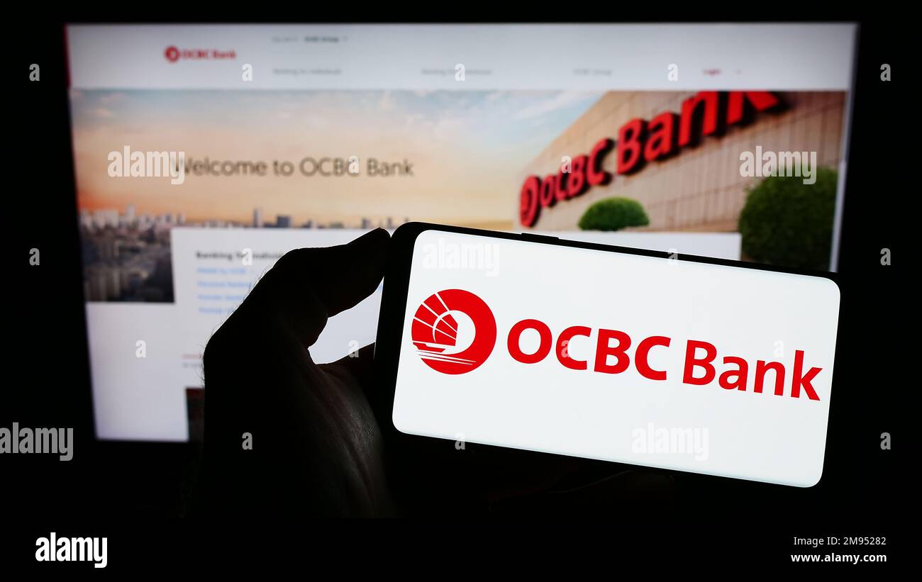 Person holding smartphone with logo of Oversea-Chinese Banking ...