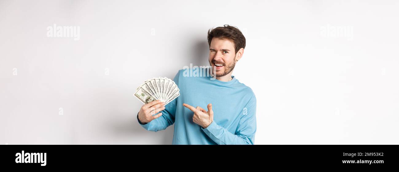 Handsome rich guy winking at camera, showing income, pointing finger at ...