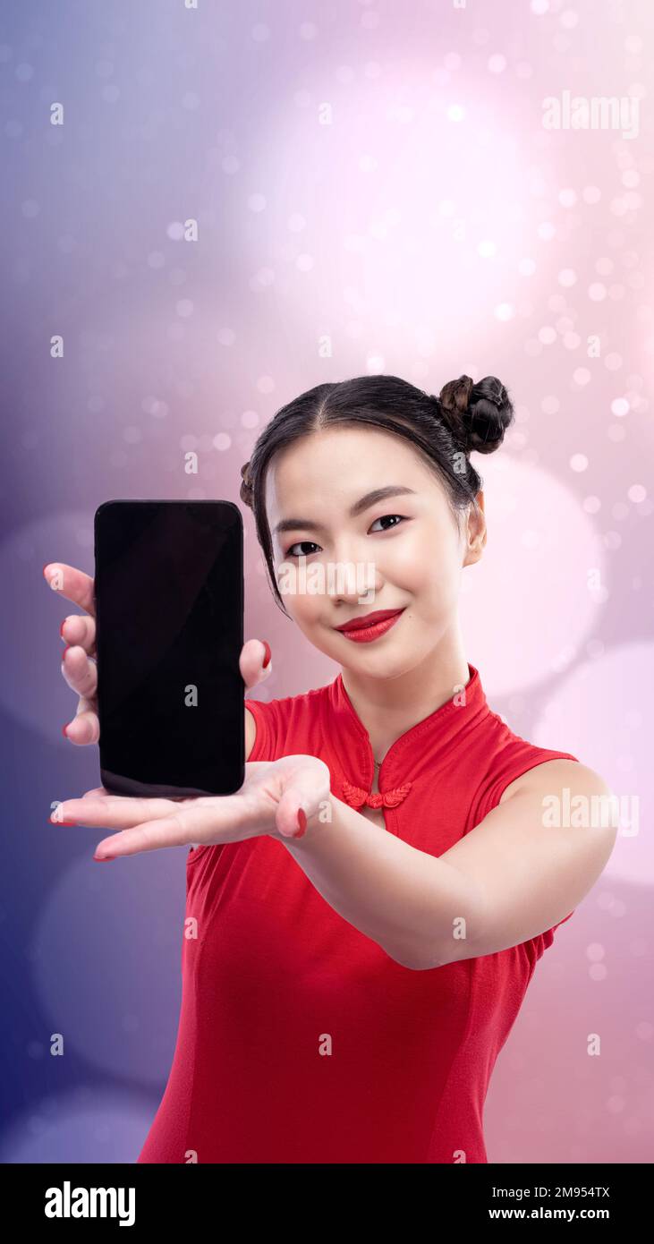 Asian Chinese woman in a cheongsam dress showing an empty mobile phone ...