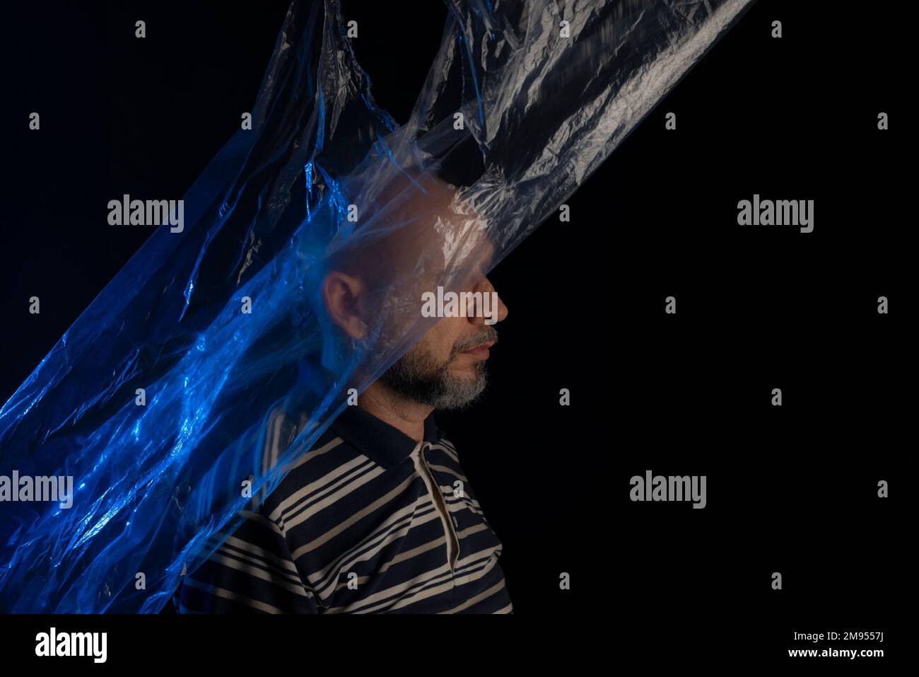 A bald mature man suffocating with a transparent plastic bag flying ...