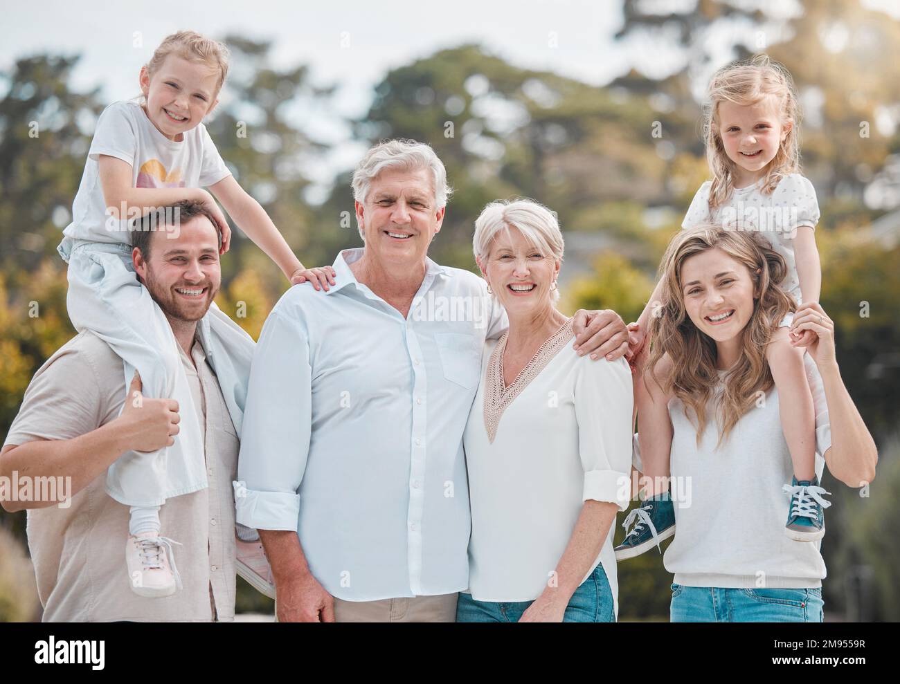 Multi-generation family standing together outside on a sunny day and ...