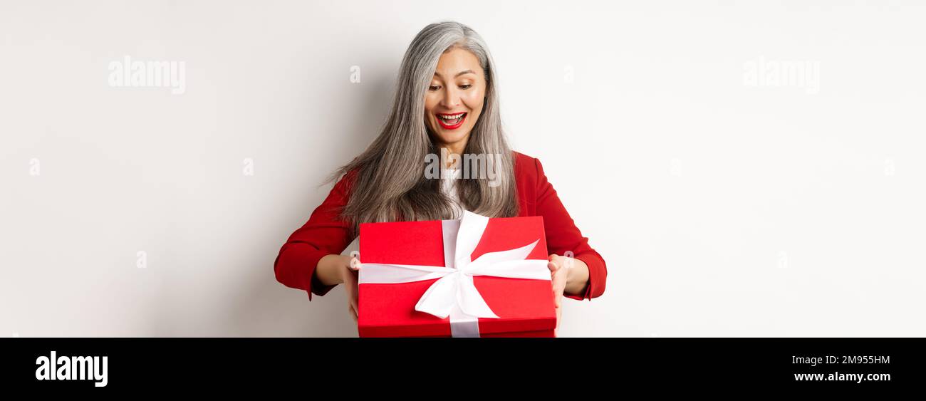 Happy elderly woman with grey hair, receive present, looking at red ...