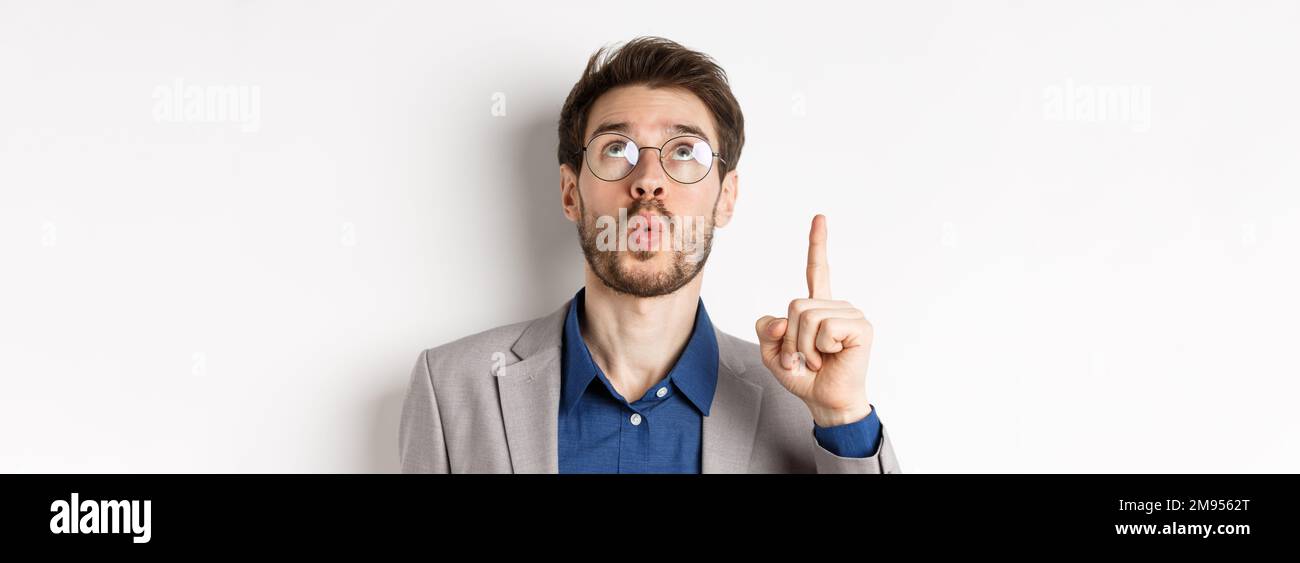 Excited handsome man in glasses and business suit, look up and pointing ...