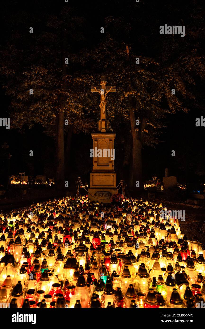 A vertical shot of a headstone with a cross surrounded by the lit ...
