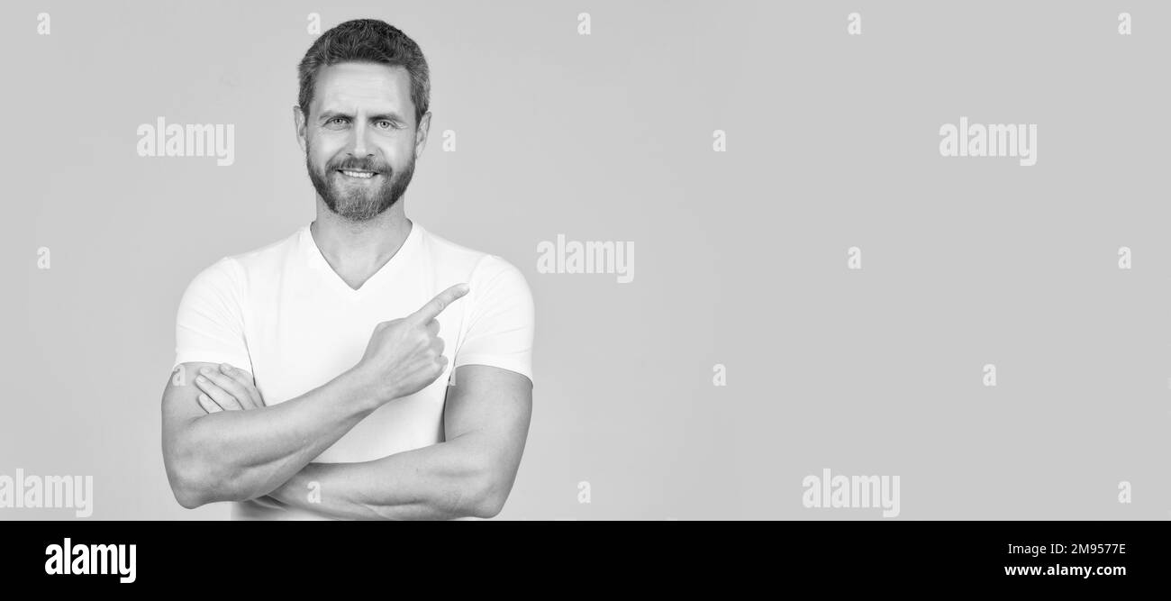 Happy handsome man smile pointing finger aside at grey background copy space, advertise. Man ...