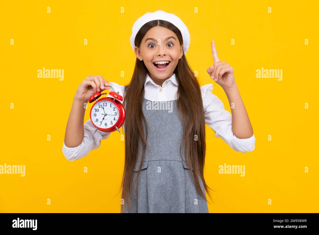 Teen student girl hold clock isolated on yellow background. Time to ...