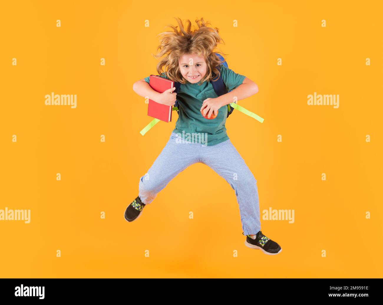 Full length of excited kid jumping. School boy in school uniform with ...