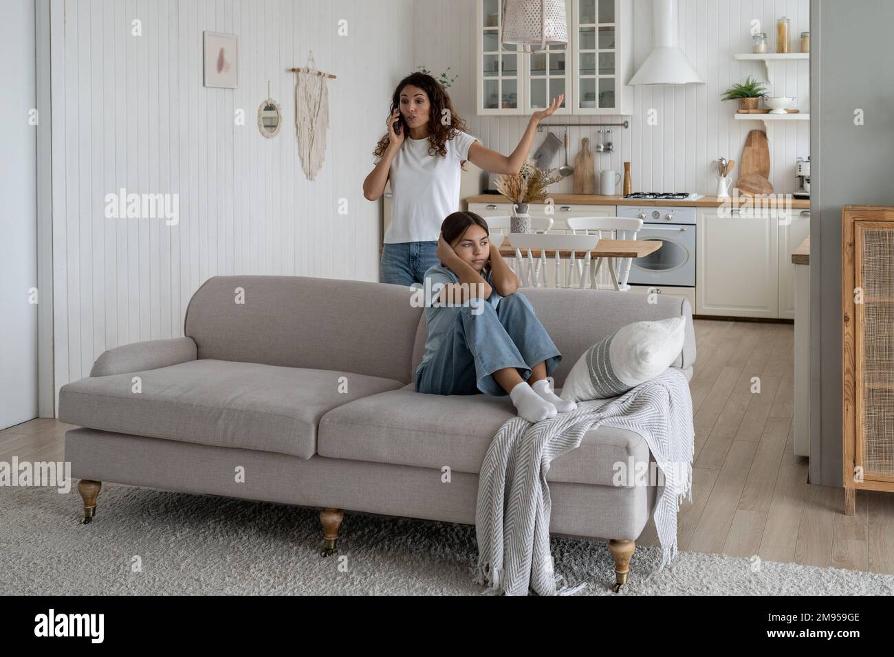 Nervous mother arguing with husband over phone in front of daughter ...