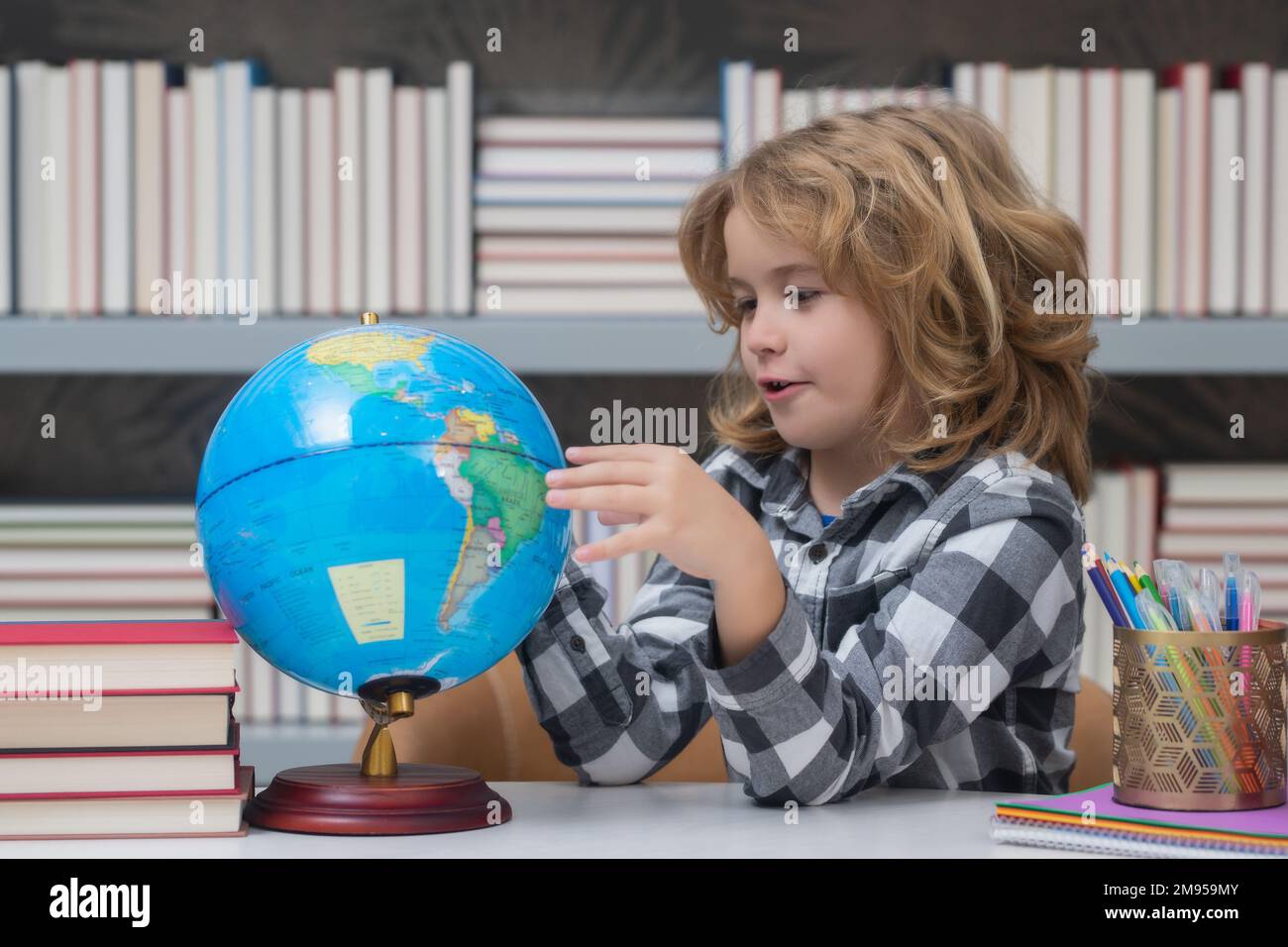 School kid pupil looking at globe in library at the elementary school ...
