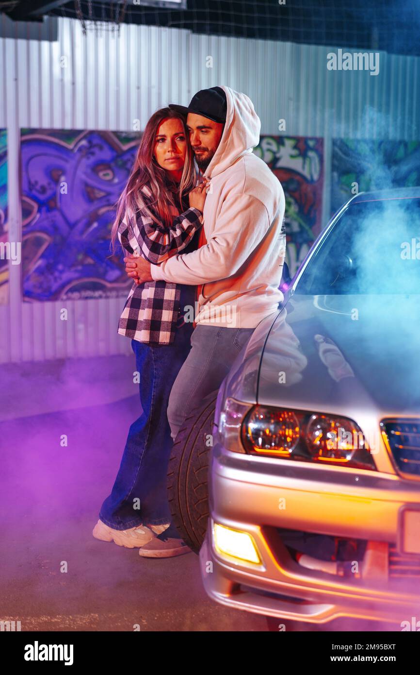 Smiling couple standing near sport car over night city background Stock ...