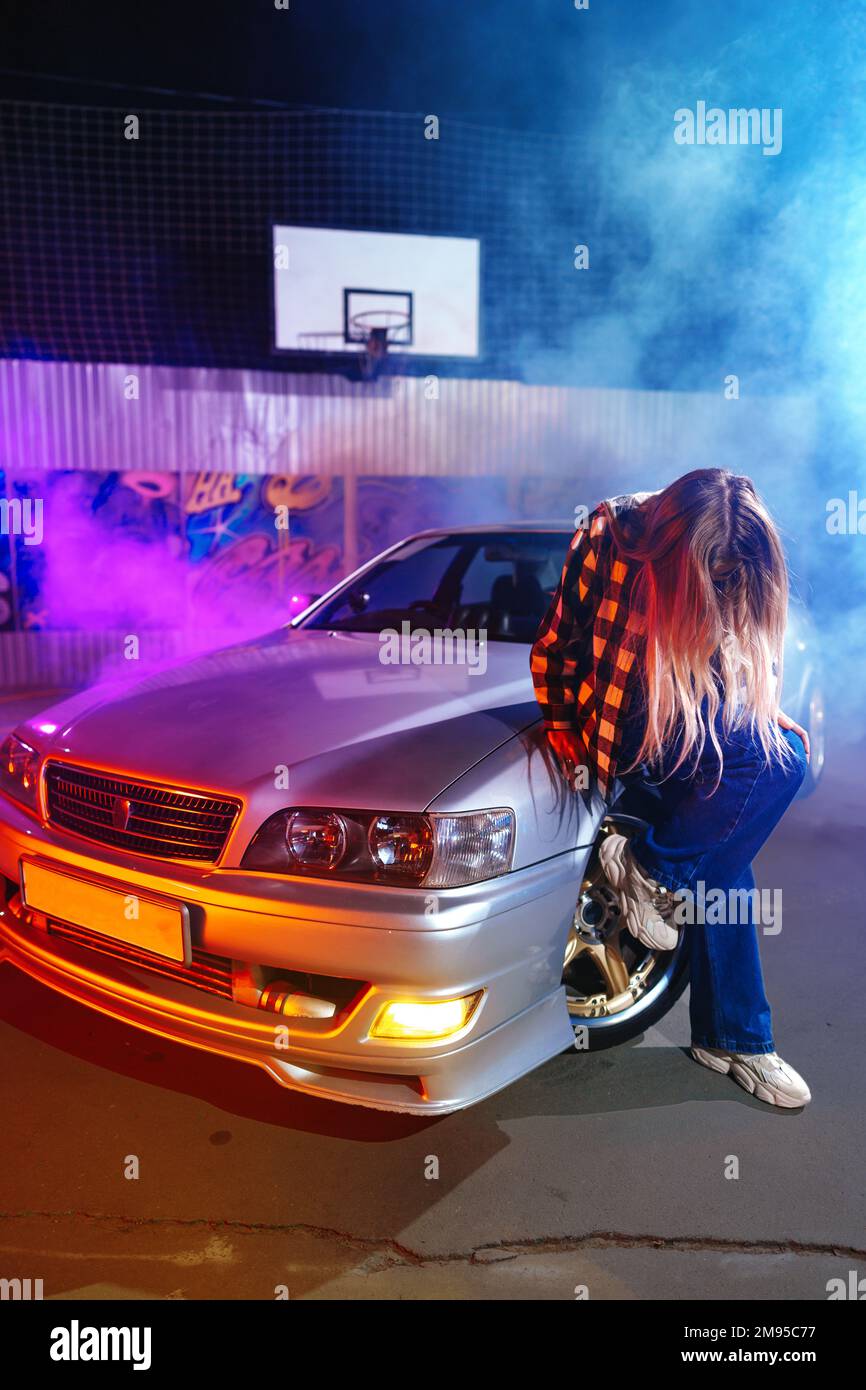 Young beautiful woman with straight long hair posing near white sport ...