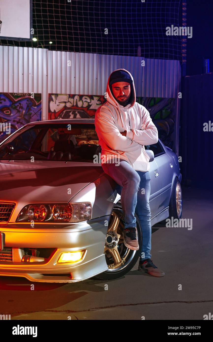 A young man standing next to his sport car at night parking Stock Photo ...