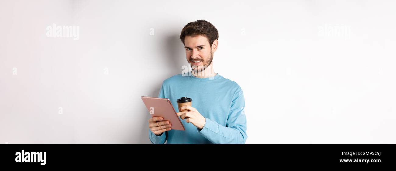 Handsome bearded man smiling at camera, drinking coffee and reading on ...