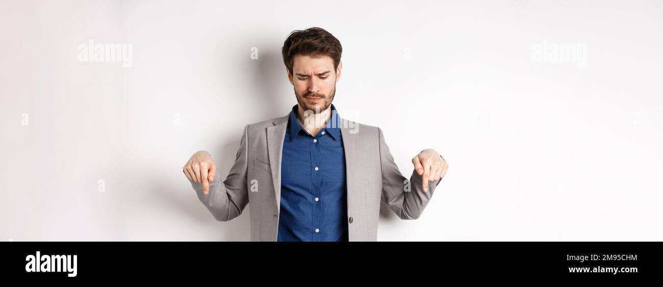 Unimpressed young businessman frowning disappointed, pointing and ...