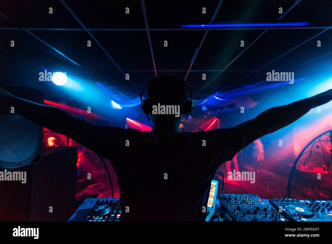 DJ in headphones waving his arms at the party night club silhouette ...