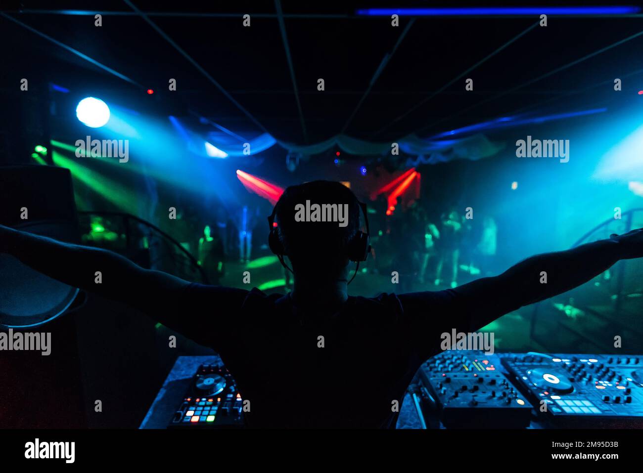 silhouette of the DJ waving his hands in different directions at a ...