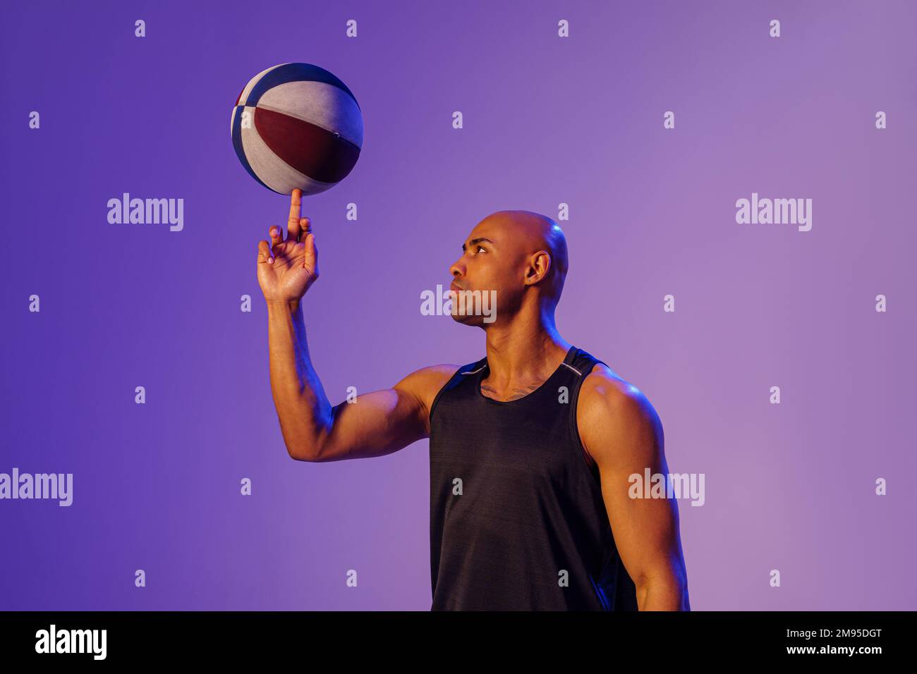 Professional basketball player spinning ball on his finger on studio ...