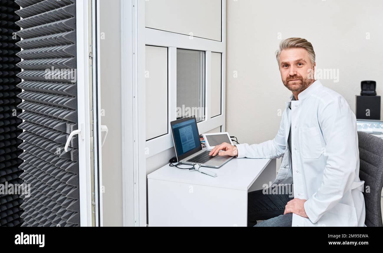 Portrait of male audiologist sitting in his office of audiology center ...
