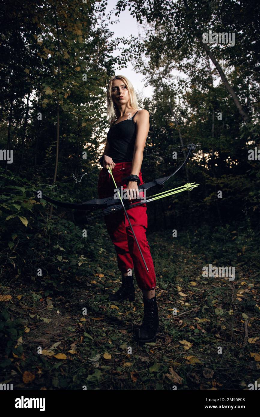A young woman holding bow and arrow in a forest Stock Photo - Alamy