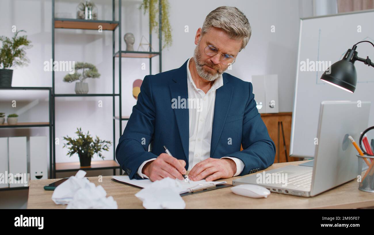 Angry furious mature man working at office throwing crumpled paper ...