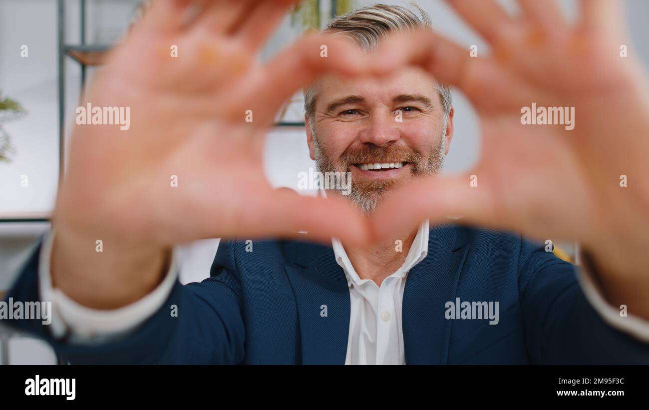 I love you. Mature business man makes symbol of love, showing heart ...