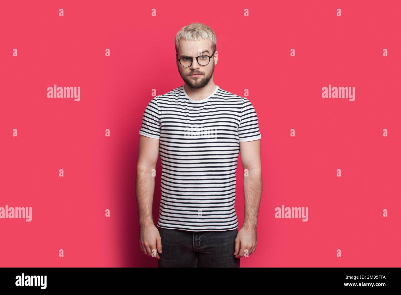 Portrait of skeptical young bearded man looking at camera isolated over ...