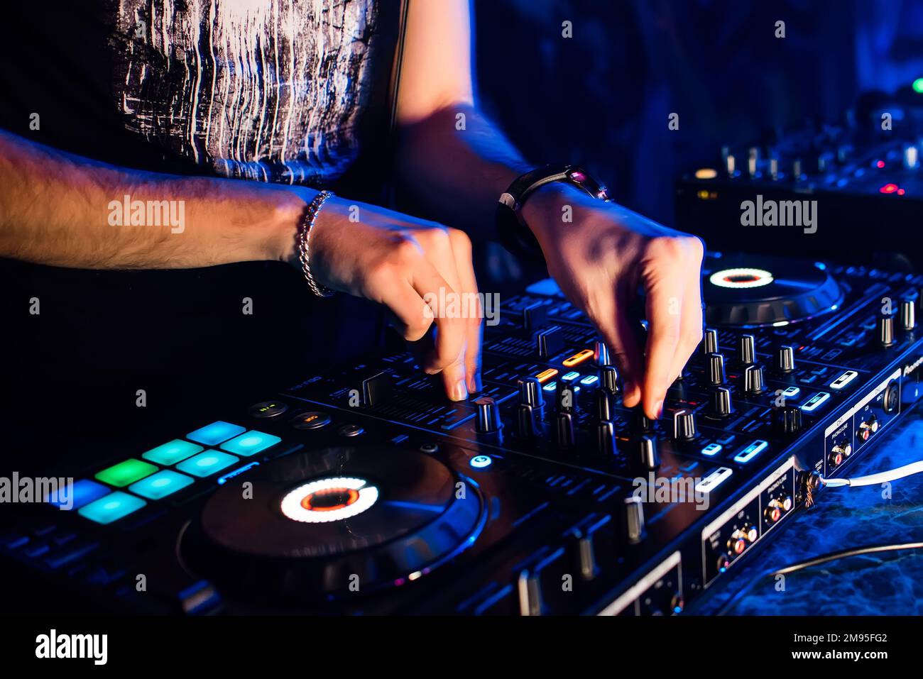 mixer and DJ booth in the nightclub with the hands of a DJ mixing music ...