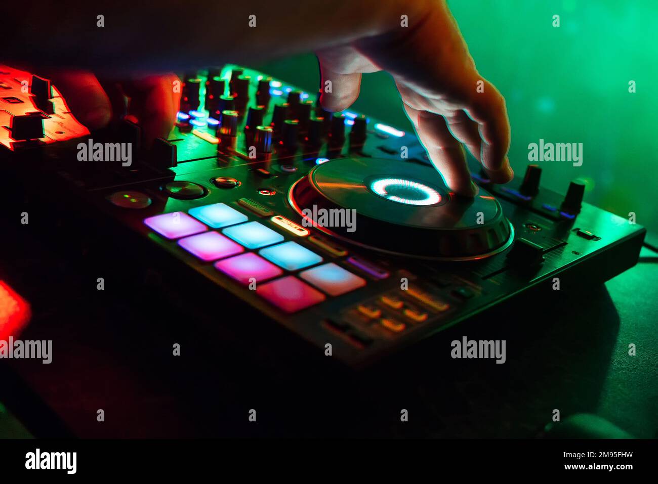 mixer and DJ booth in the nightclub with the arms of the DJ managing ...
