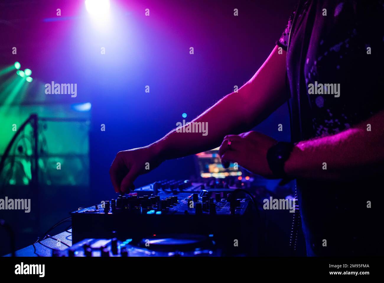 DJ in the night club playing at a professional mixer, color-changing ...