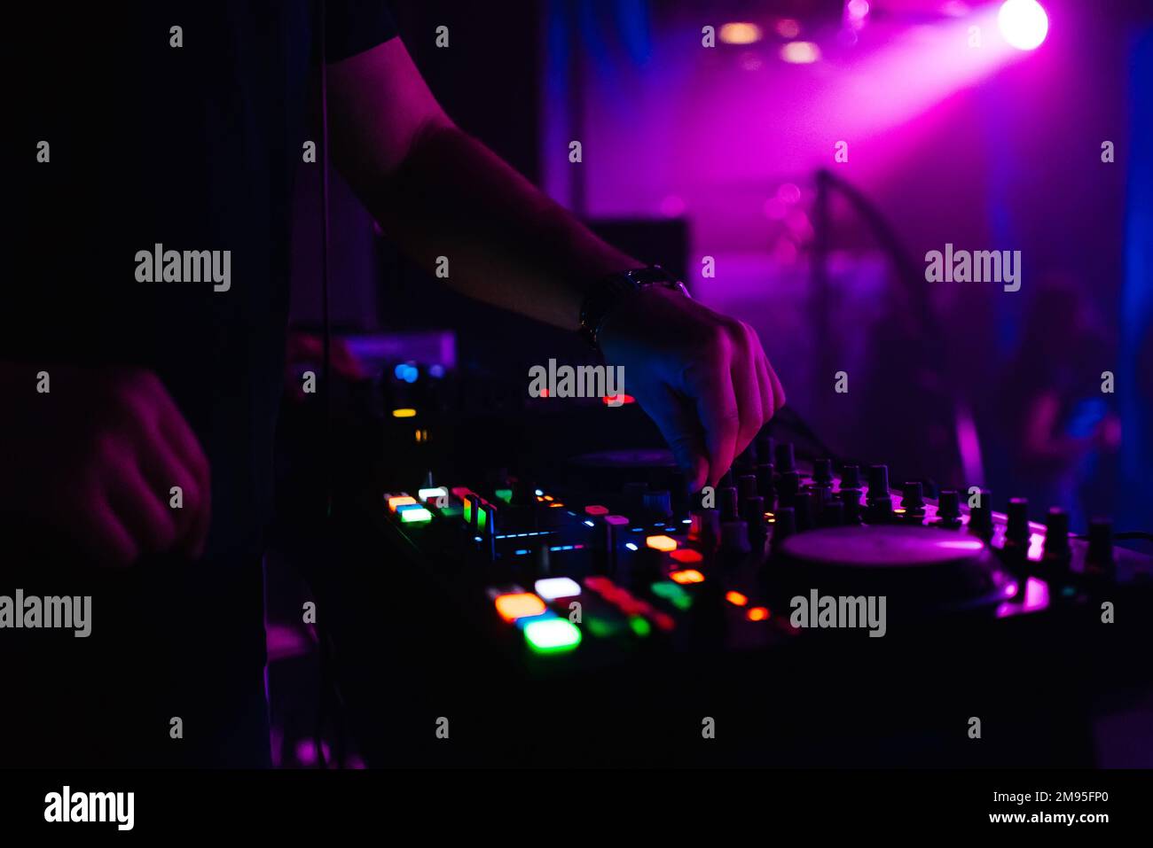 DJ controls the music in the nightclub moving the controllers on the ...